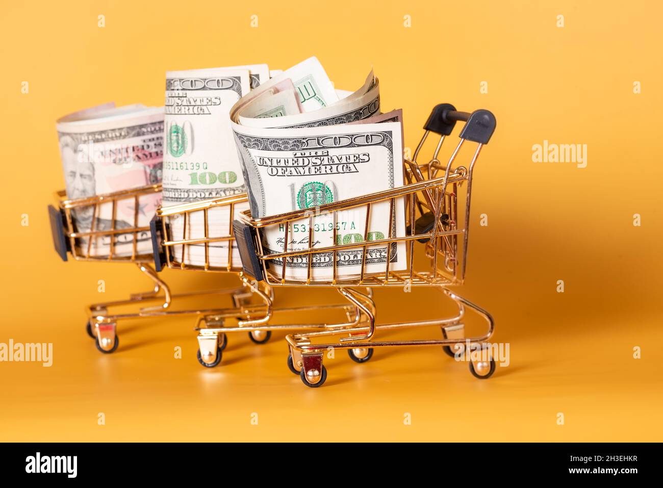 Financial concept. Shopping carts with dollars paper bills on a yellow ...