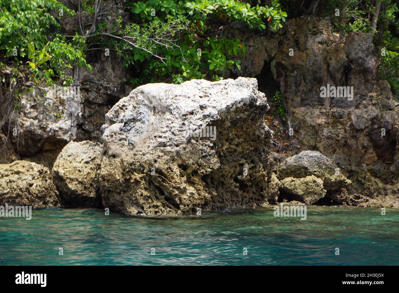 Rocky cliffs near the blue water with coral reef at the beach in ...