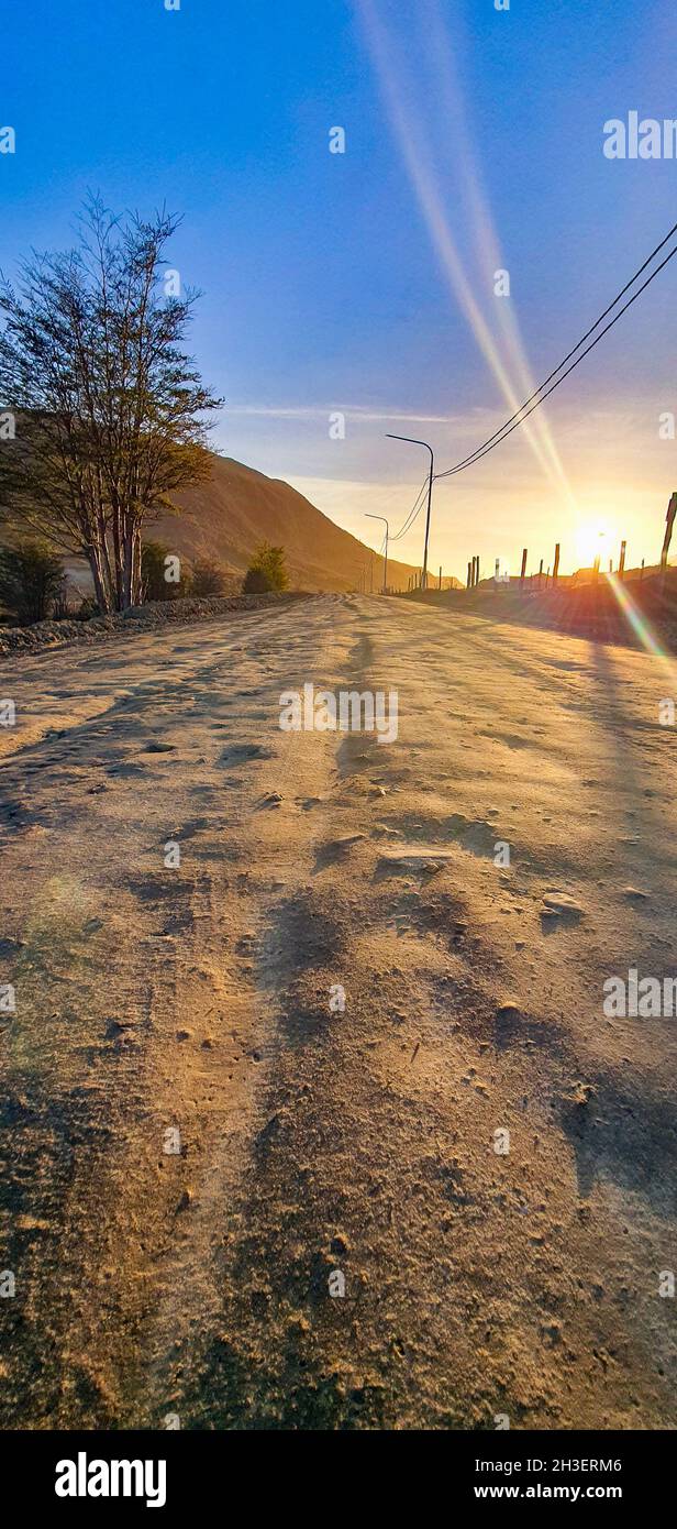 Vertical shot of a sandy road and a beautiful sunrise in the background ...