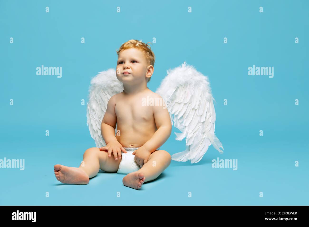 Full-length portrait of little boy, child in diaper with angel wings ...