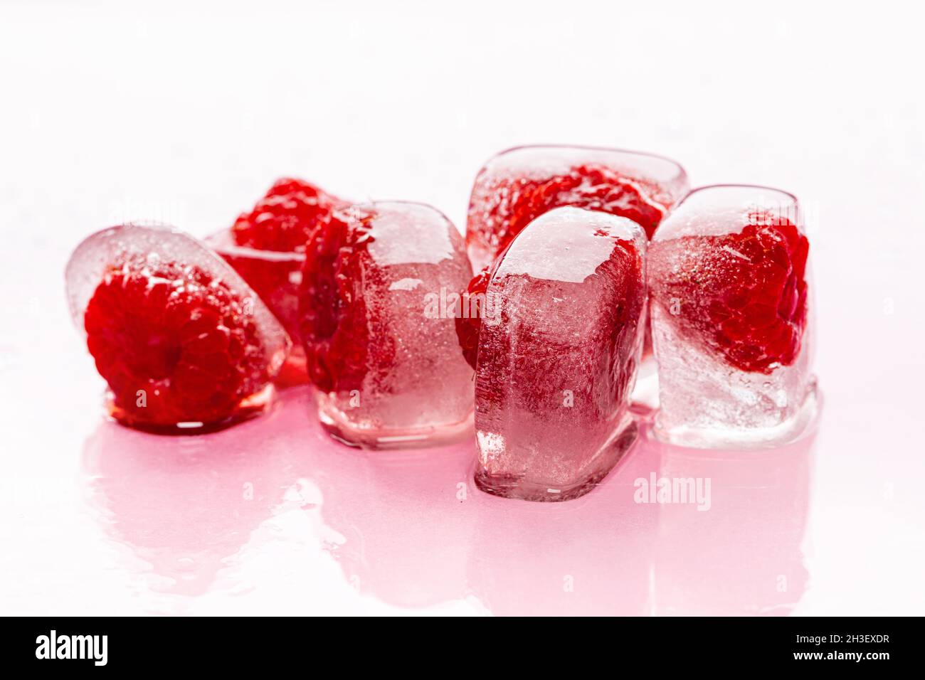 Raspberry ice cubes on pink glossy background Stock Photo - Alamy