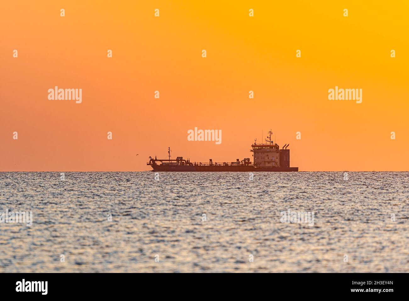 Sunset on the Sea with a Freight Ship Stock Photo - Alamy
