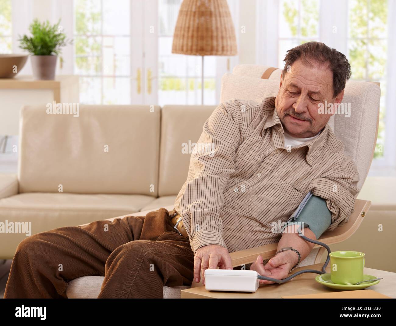 Old man measuring blood pressure at home Stock Photo - Alamy