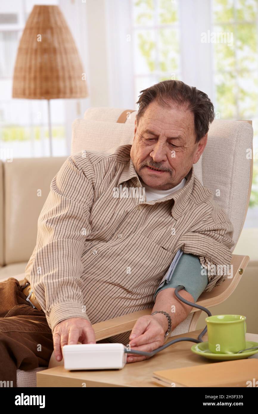 Old man measuring blood pressure at home Stock Photo - Alamy