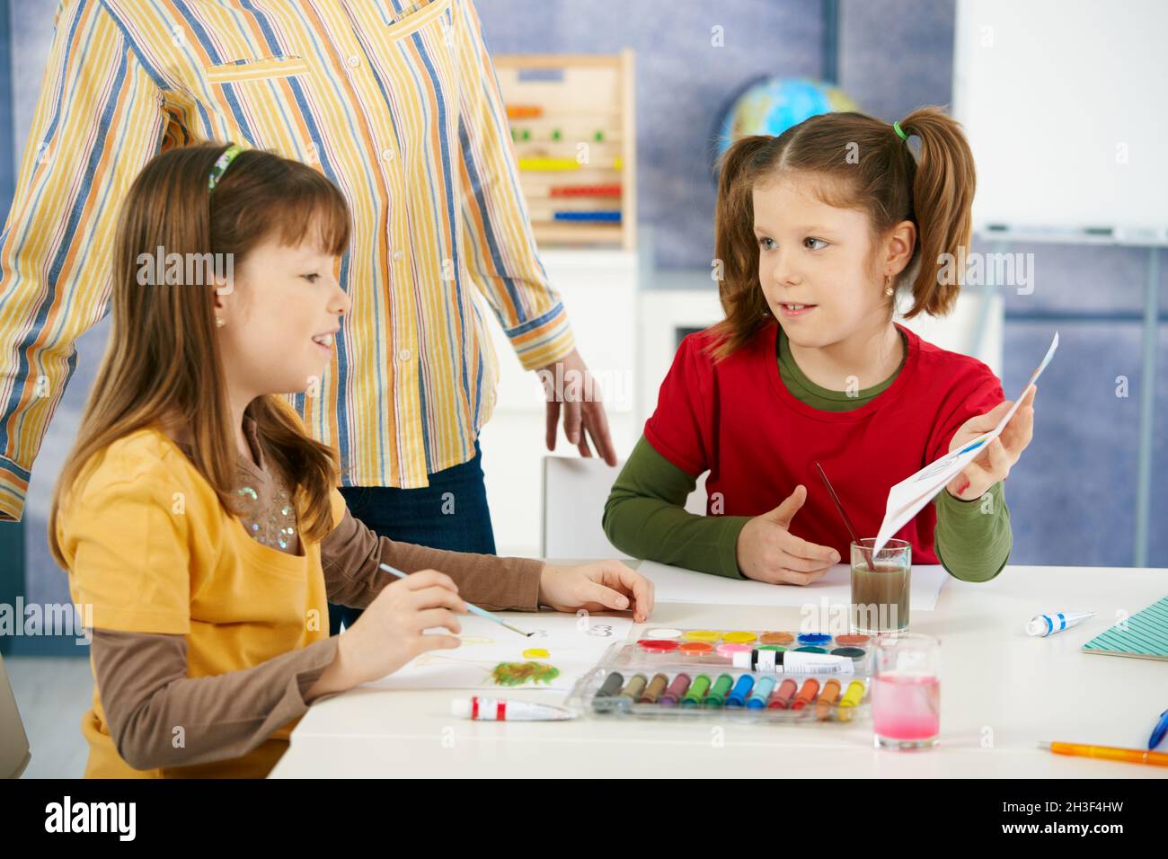 Elementary age children painting in classroom Stock Photo - Alamy
