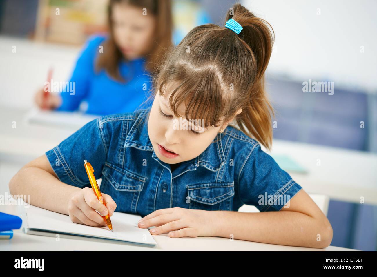 Young girl writing at school Stock Photo - Alamy