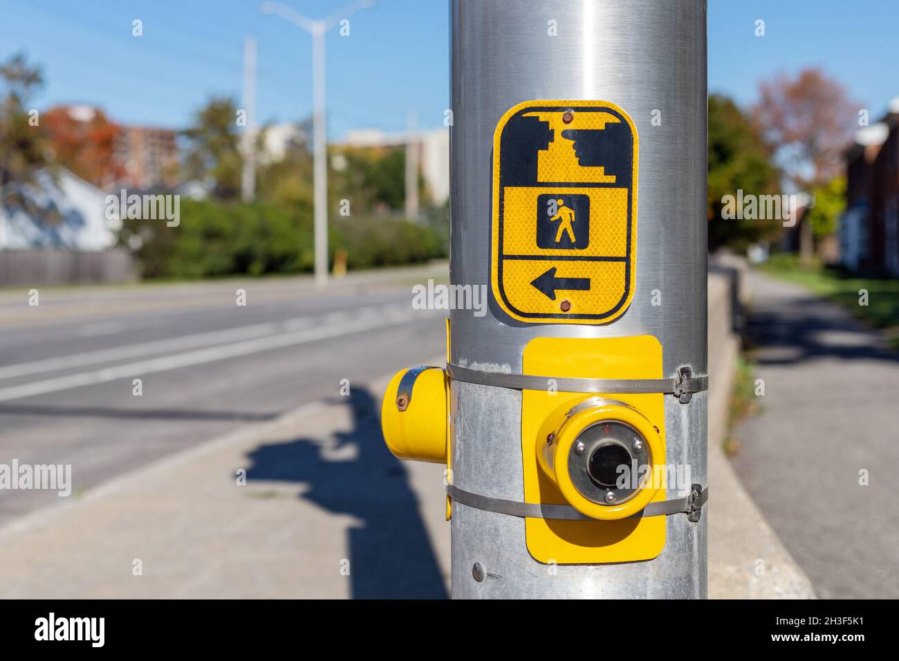 Yellow pedestrian push button sign on traffic signal pole at crosswalk ...