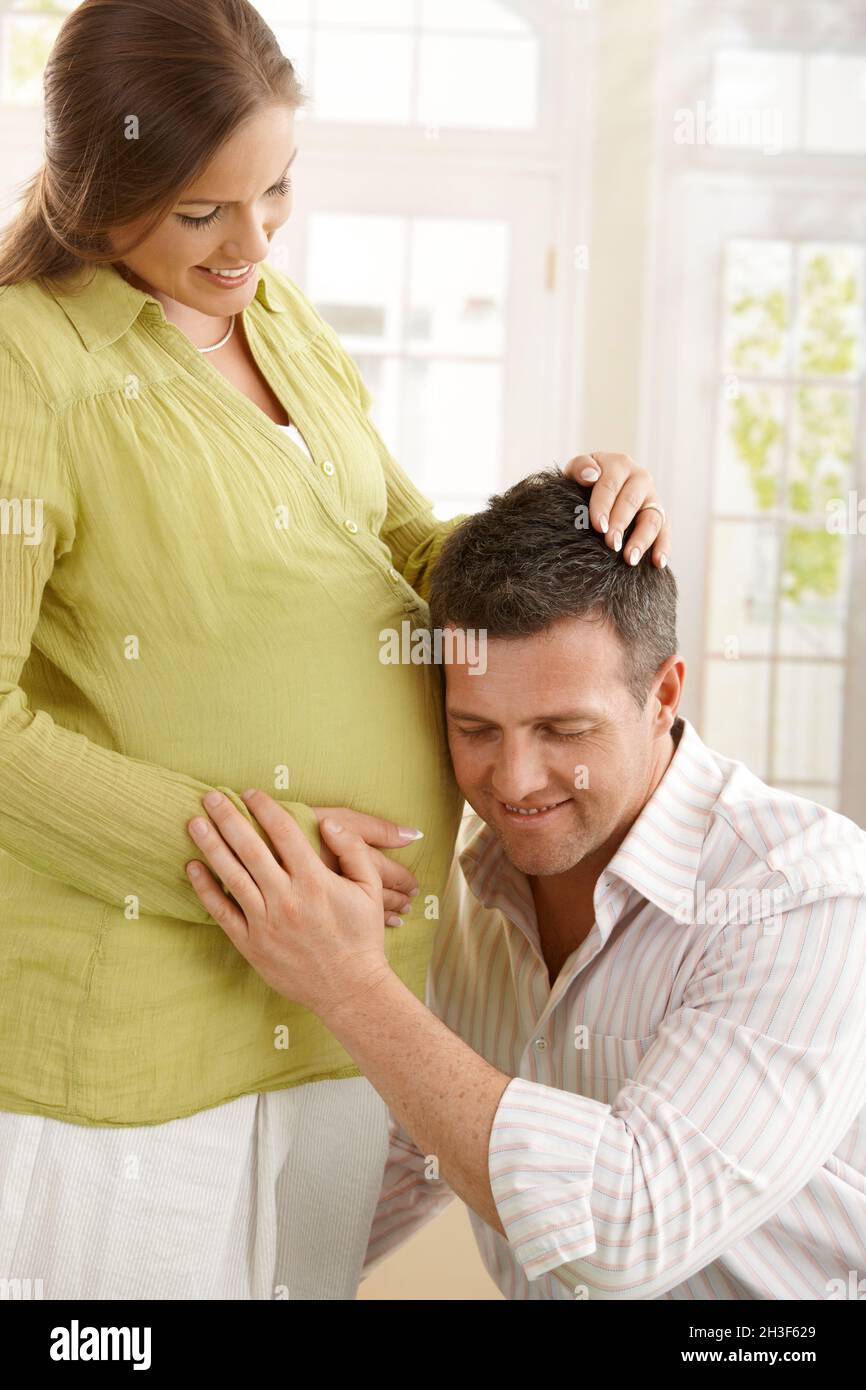 Dad listening to baby in belly Stock Photo - Alamy