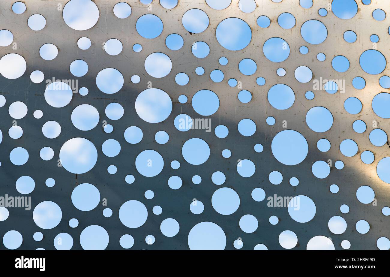 Polished stainless steel plate with round holes pattern is under blue ...