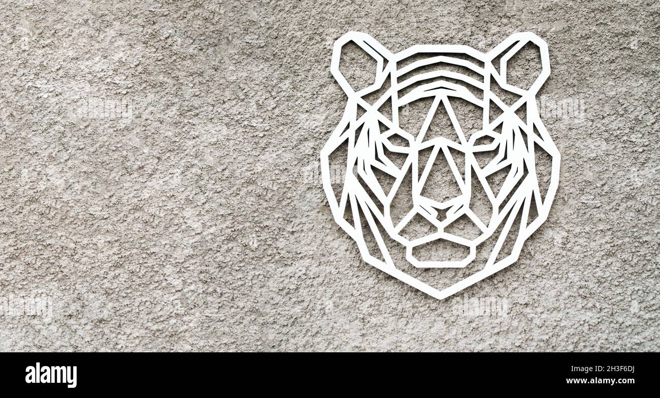 Large flat white tiger head on gray rough stone wall, plaster ...
