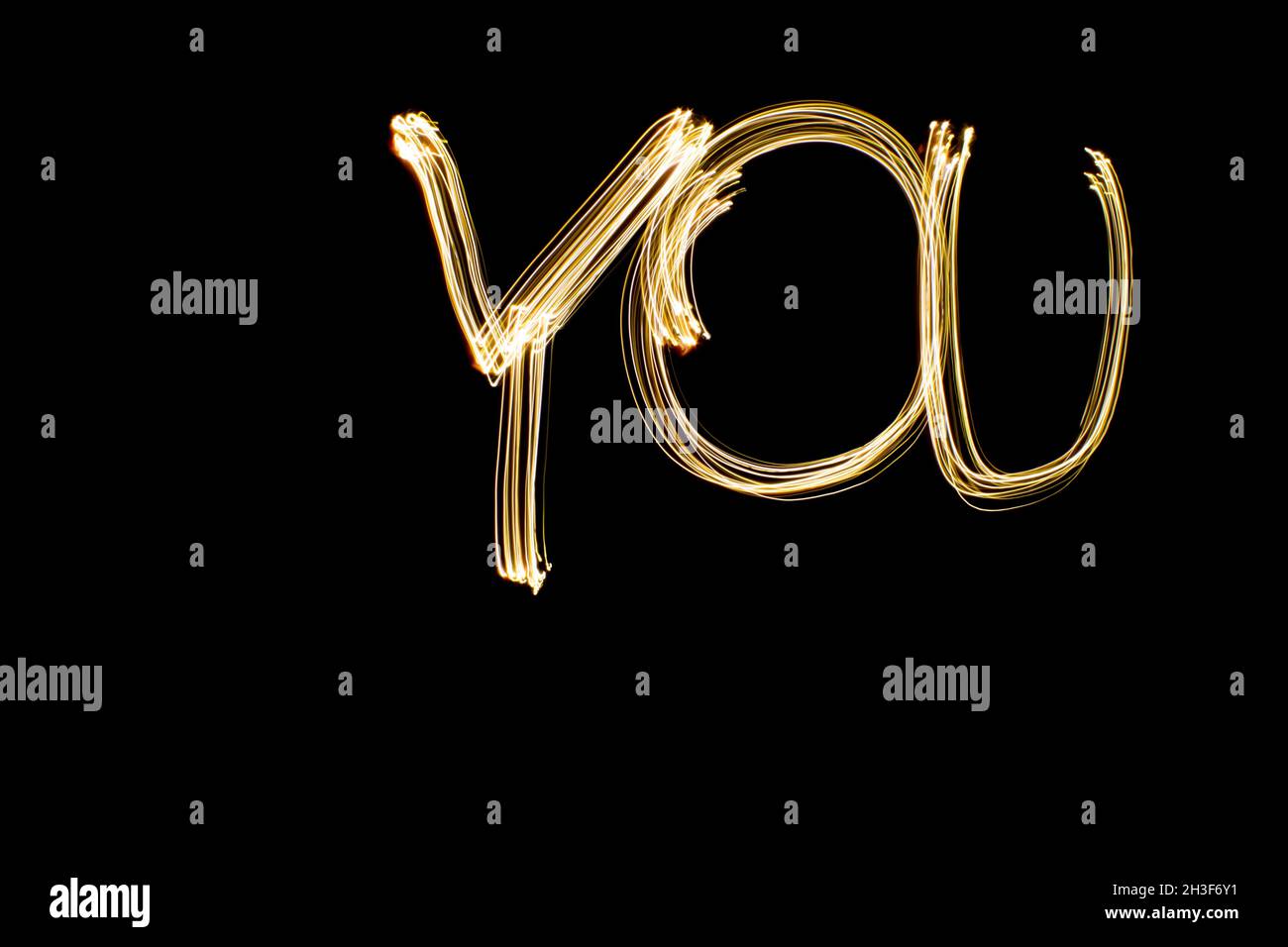 The word 'you' written in light painting technique against a black ...