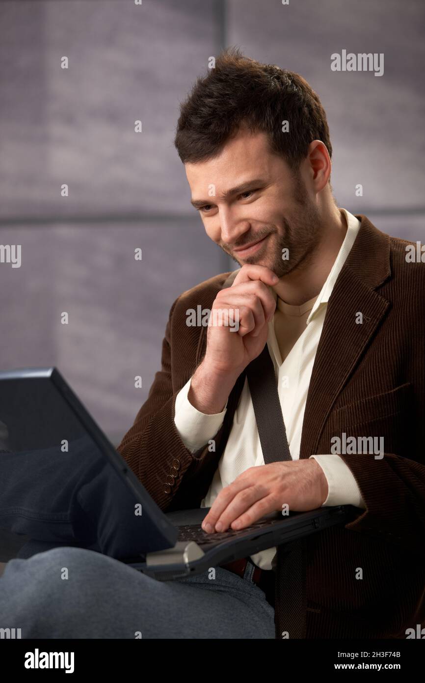 Happy guy smiling with laptop Stock Photo - Alamy