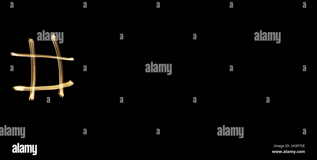 Neon hashtag sign. Light painting yellow hashtag sign against black ...