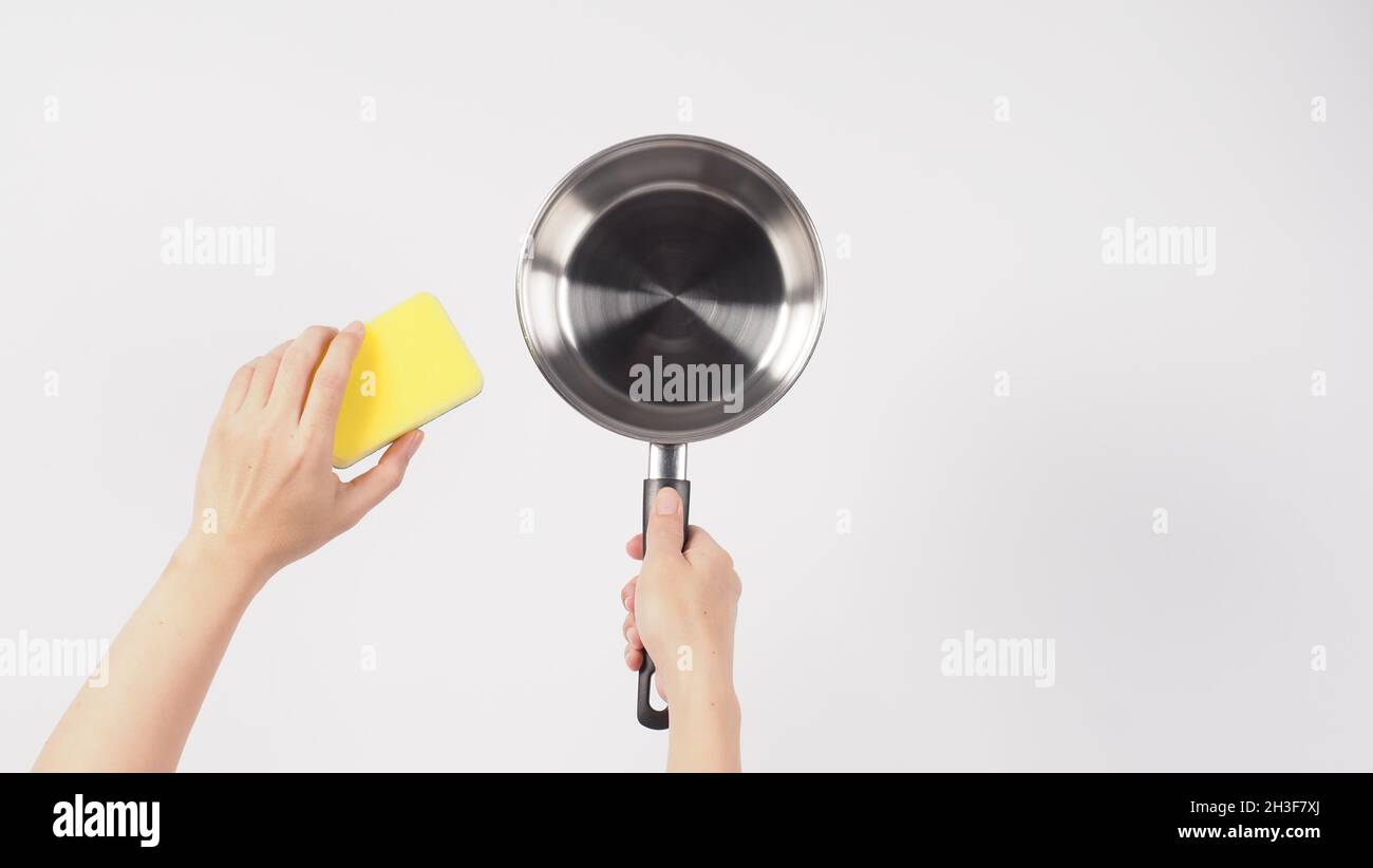 Pot cleaning. Man hand on white background cleaning the non stick pot ...