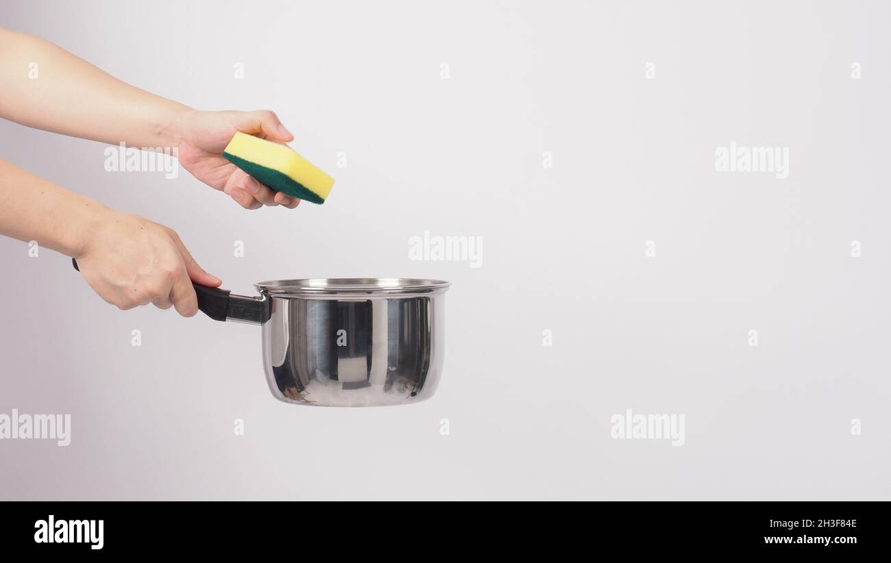 Pot cleaning. Man hand on white background cleaning the non stick pot ...