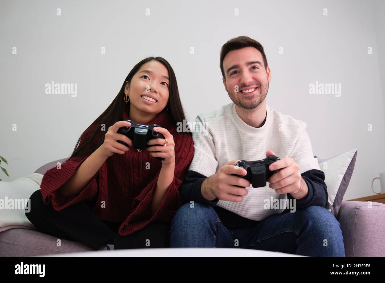 Young multiracial couple playing video games and using joystick ...