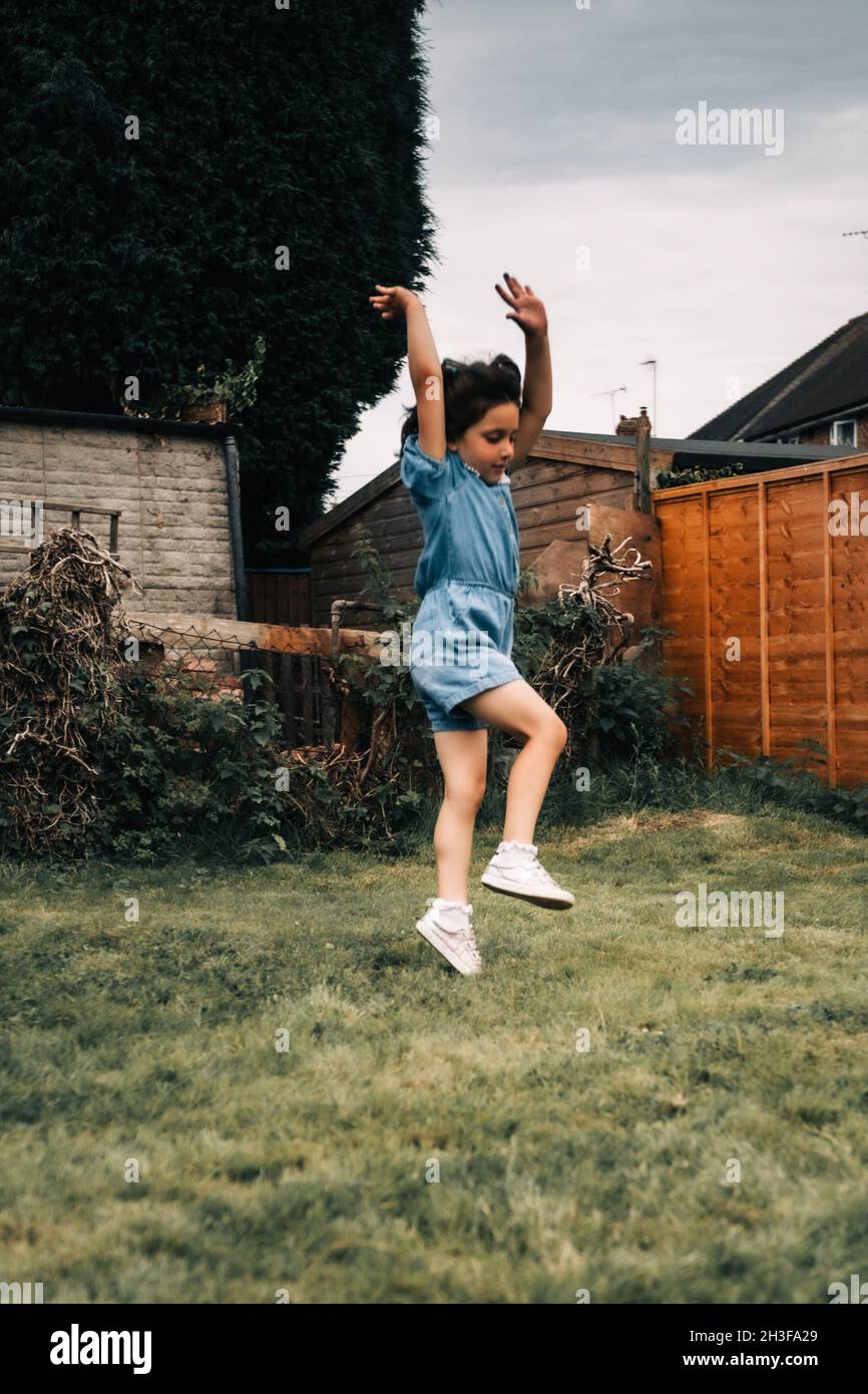 Vertical image of a cute jumping girl Stock Photo - Alamy