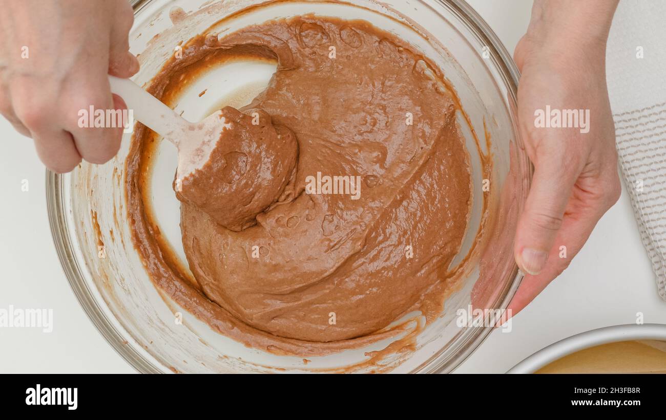 Chocolate cake recipe. Mixing cake batter in a glass bowl. Close up ...