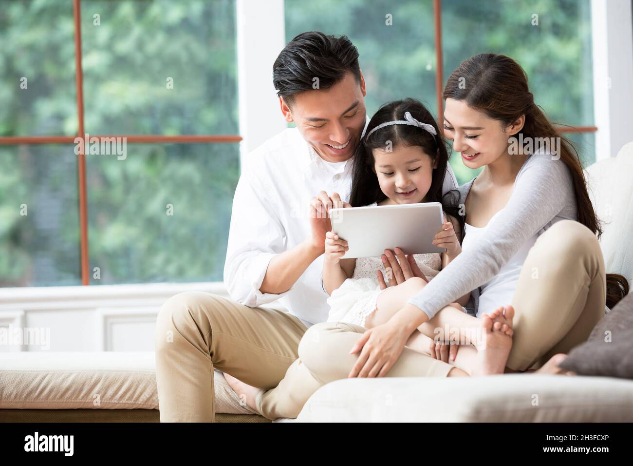 Family of three playing a tablet computer Stock Photo - Alamy