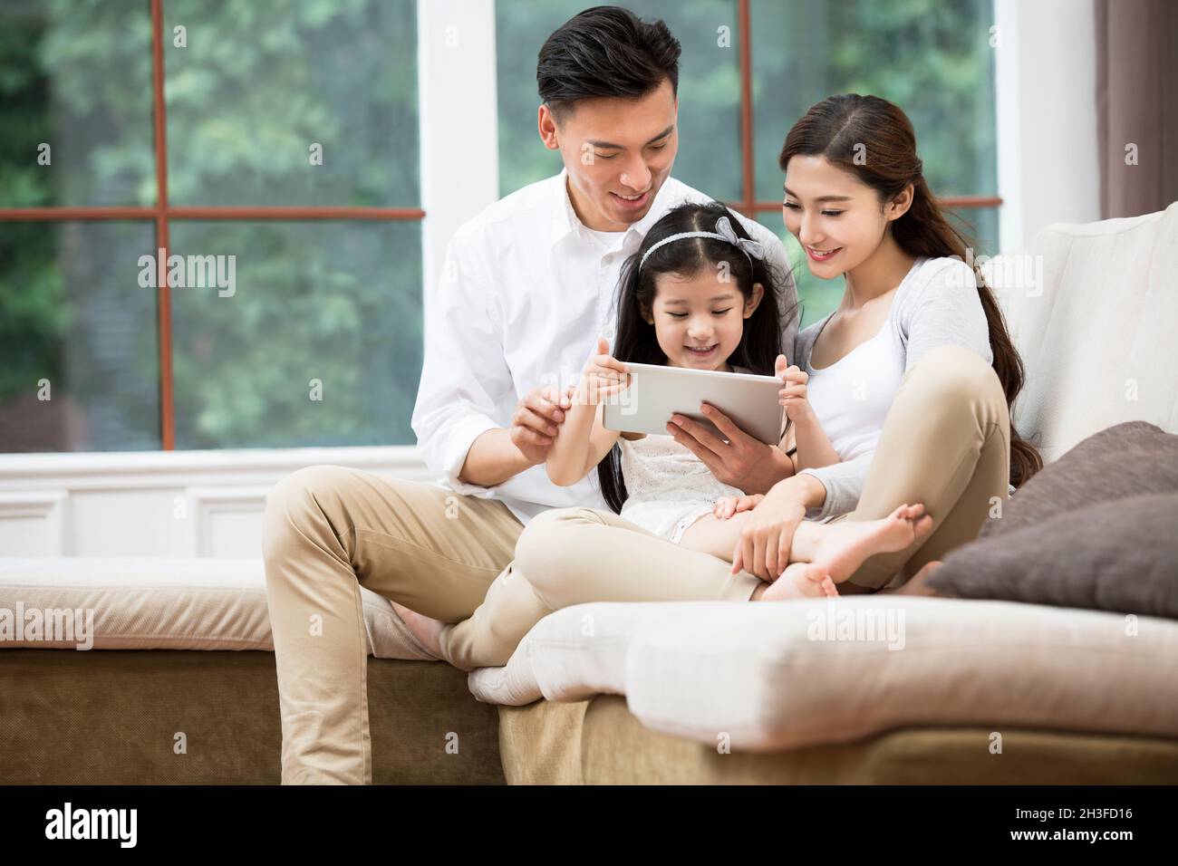 Family of three playing a tablet computer Stock Photo - Alamy