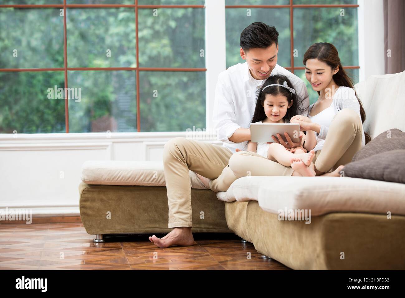 Family of three playing a tablet computer Stock Photo - Alamy