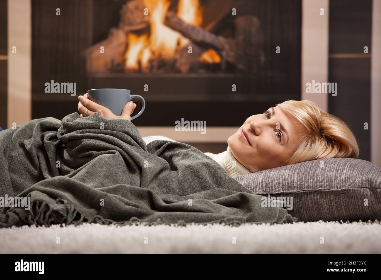 Woman resting beside fireplace Stock Photo - Alamy