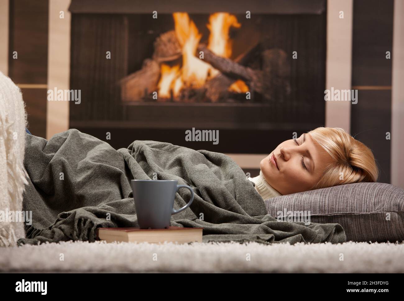 Woman sleeping beside fireplace Stock Photo - Alamy