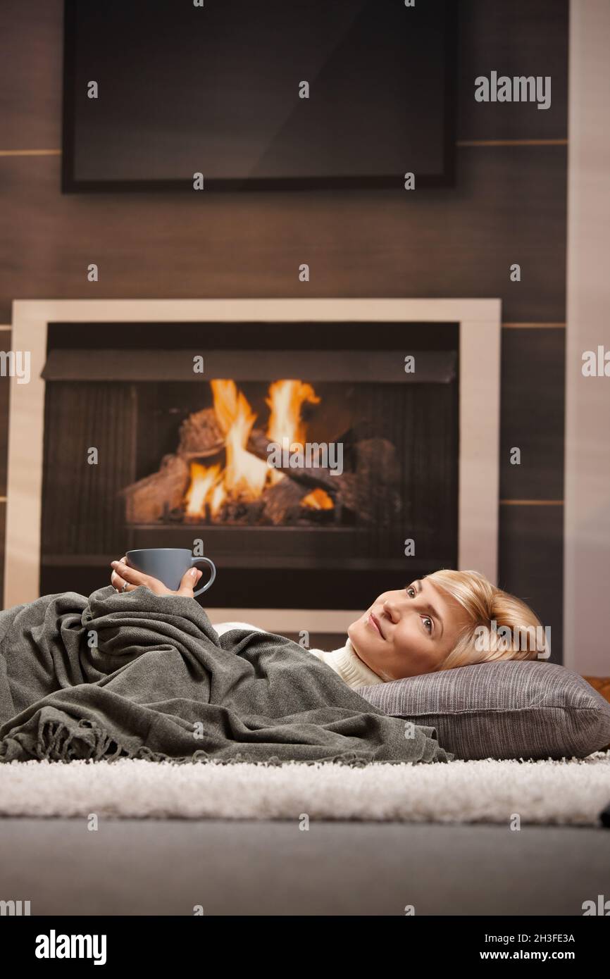Woman resting beside fireplace Stock Photo - Alamy