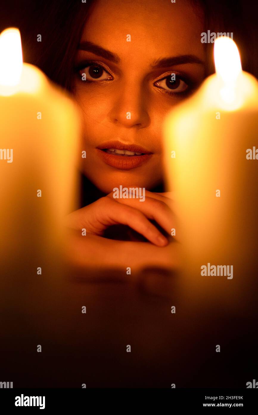 The girl looks between two candles. The mysterious look of a woman ...