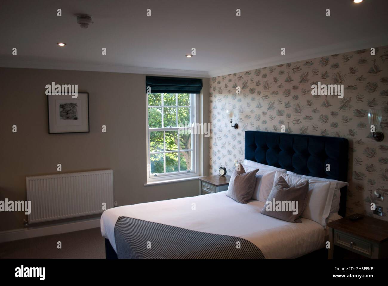 Room interior with bed, radiator, picture, window and side table of pub ...