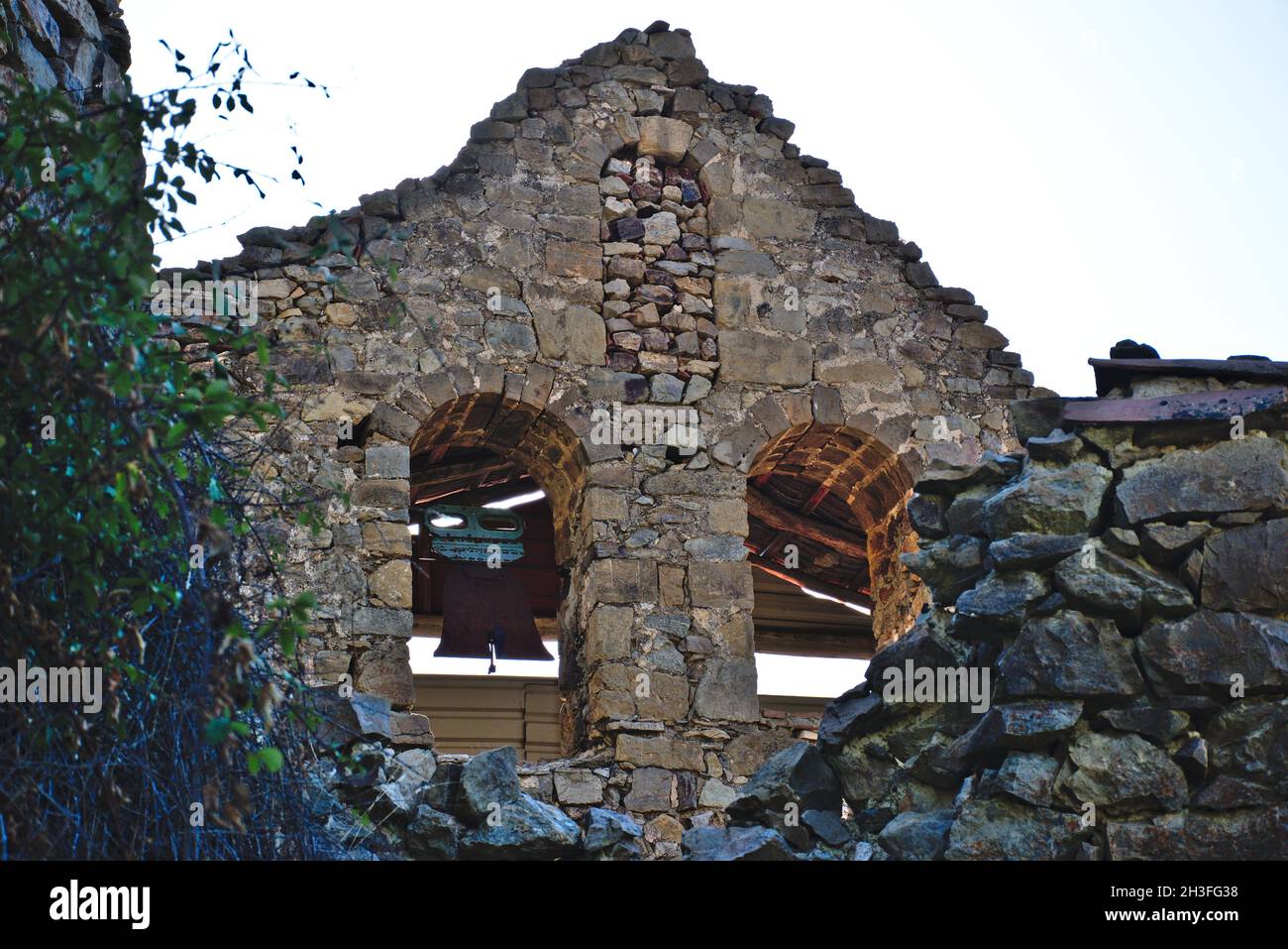 Steeple of the church of Armejún seen through a semi-ruined dry stone ...