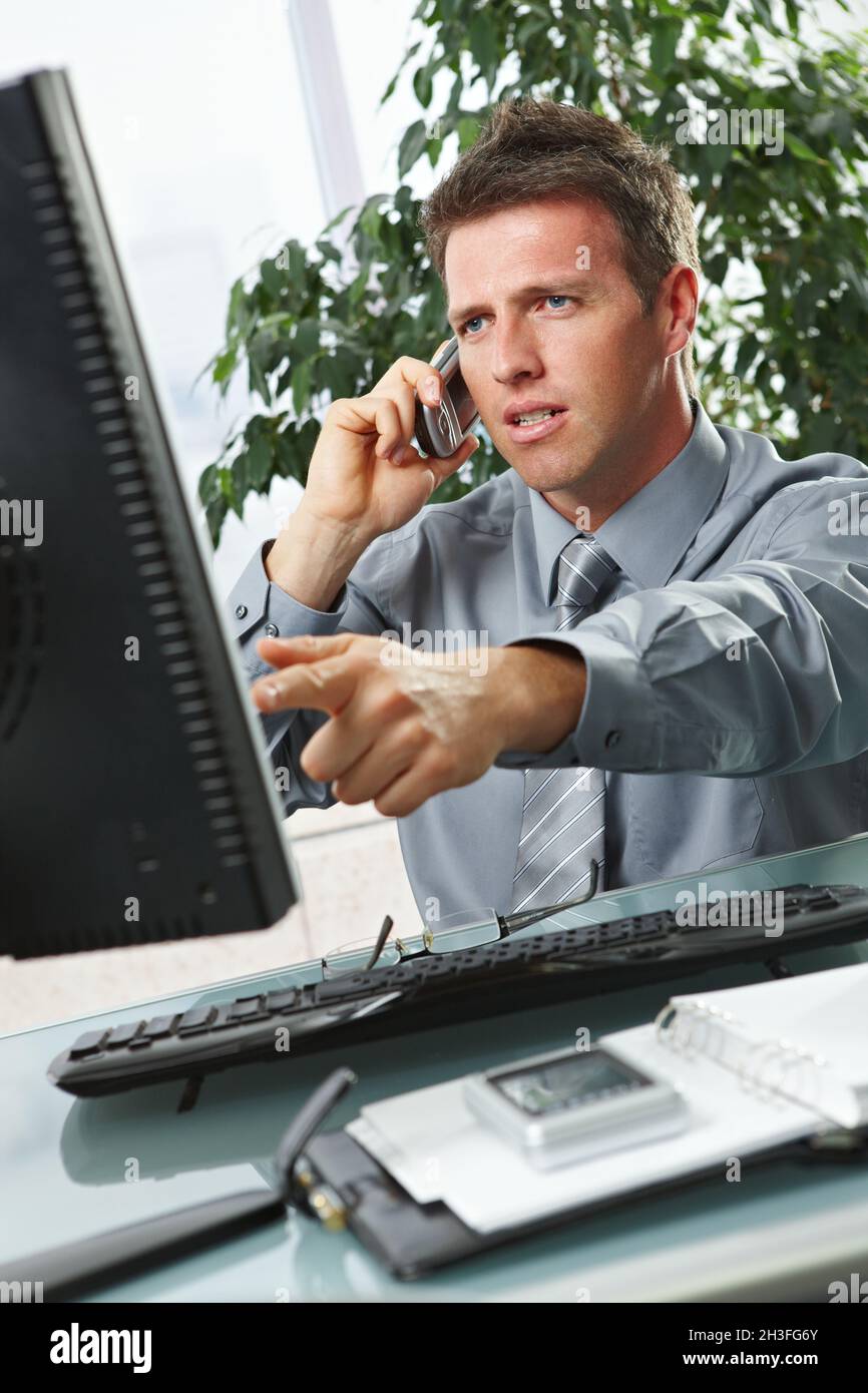 Businessman pointing at screen at desk Stock Photo - Alamy