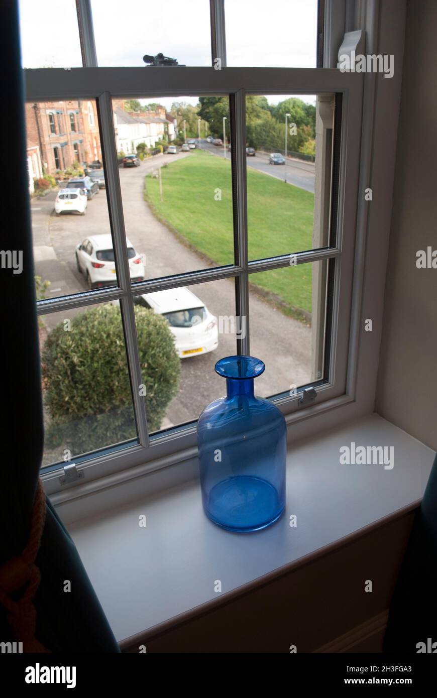 Room interior looking through window with curtains and blue bottle at ...