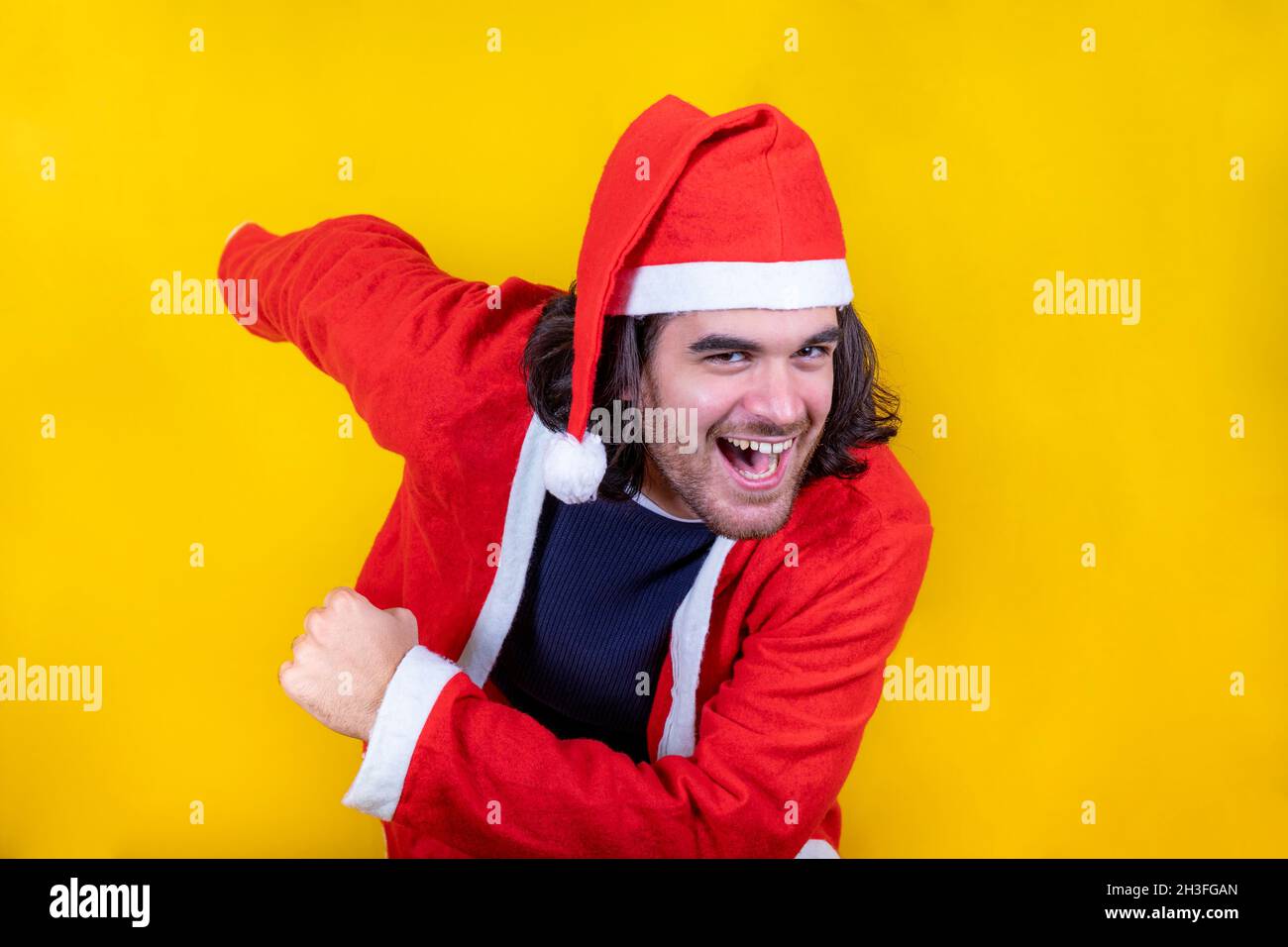Beautiful man is dressed as Santa Claus and is dancing happy. The young ...