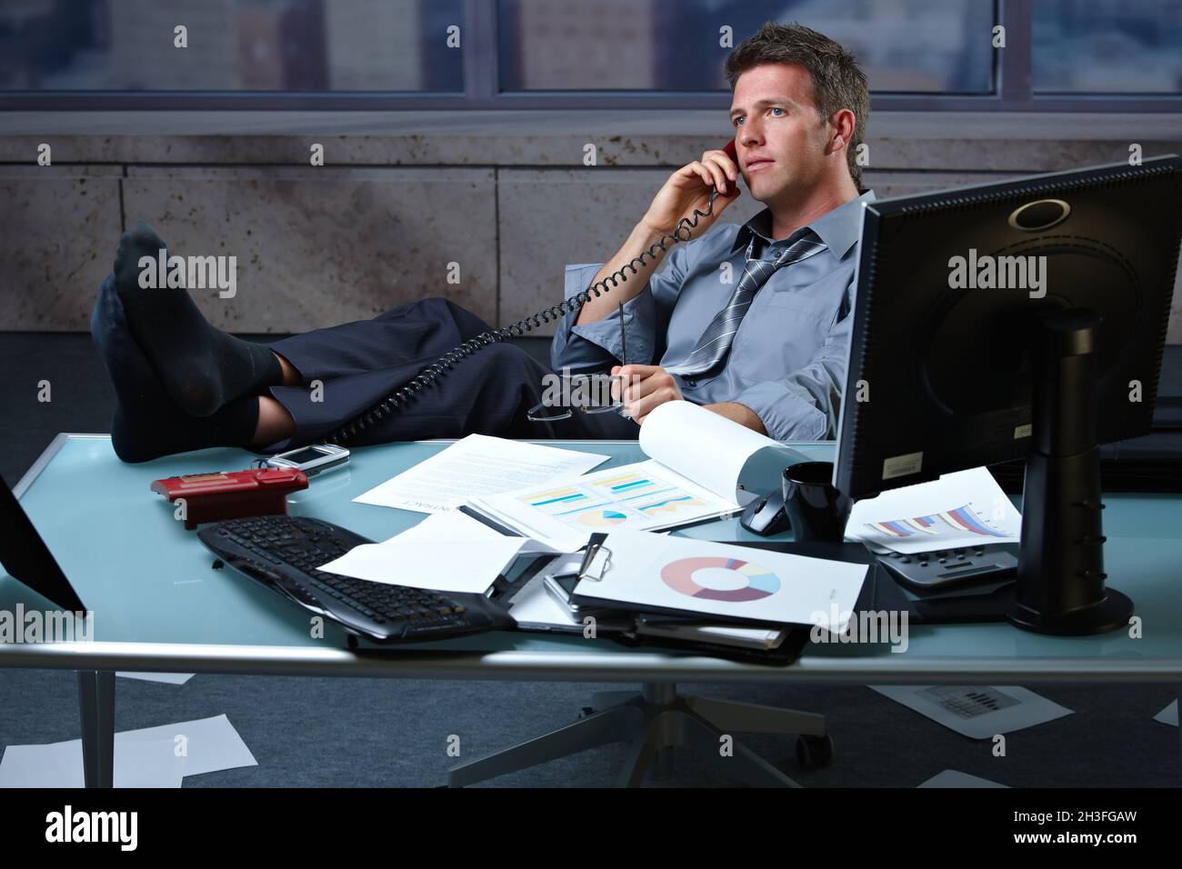 Businessman on call feet up on office desk Stock Photo - Alamy