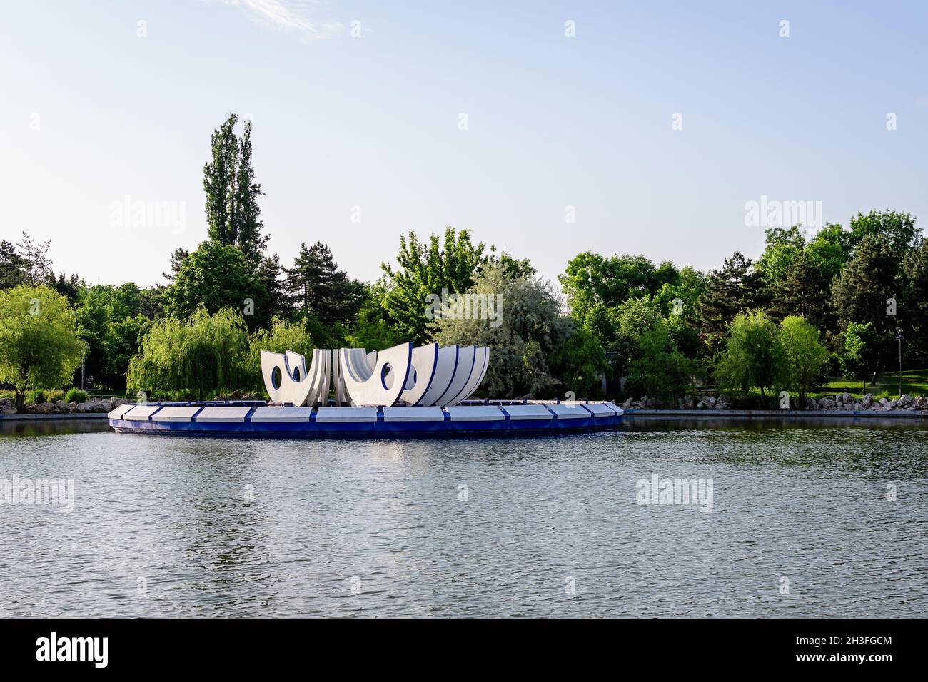 Landscape with the lake, decorative fountain and vivid green trees in ...