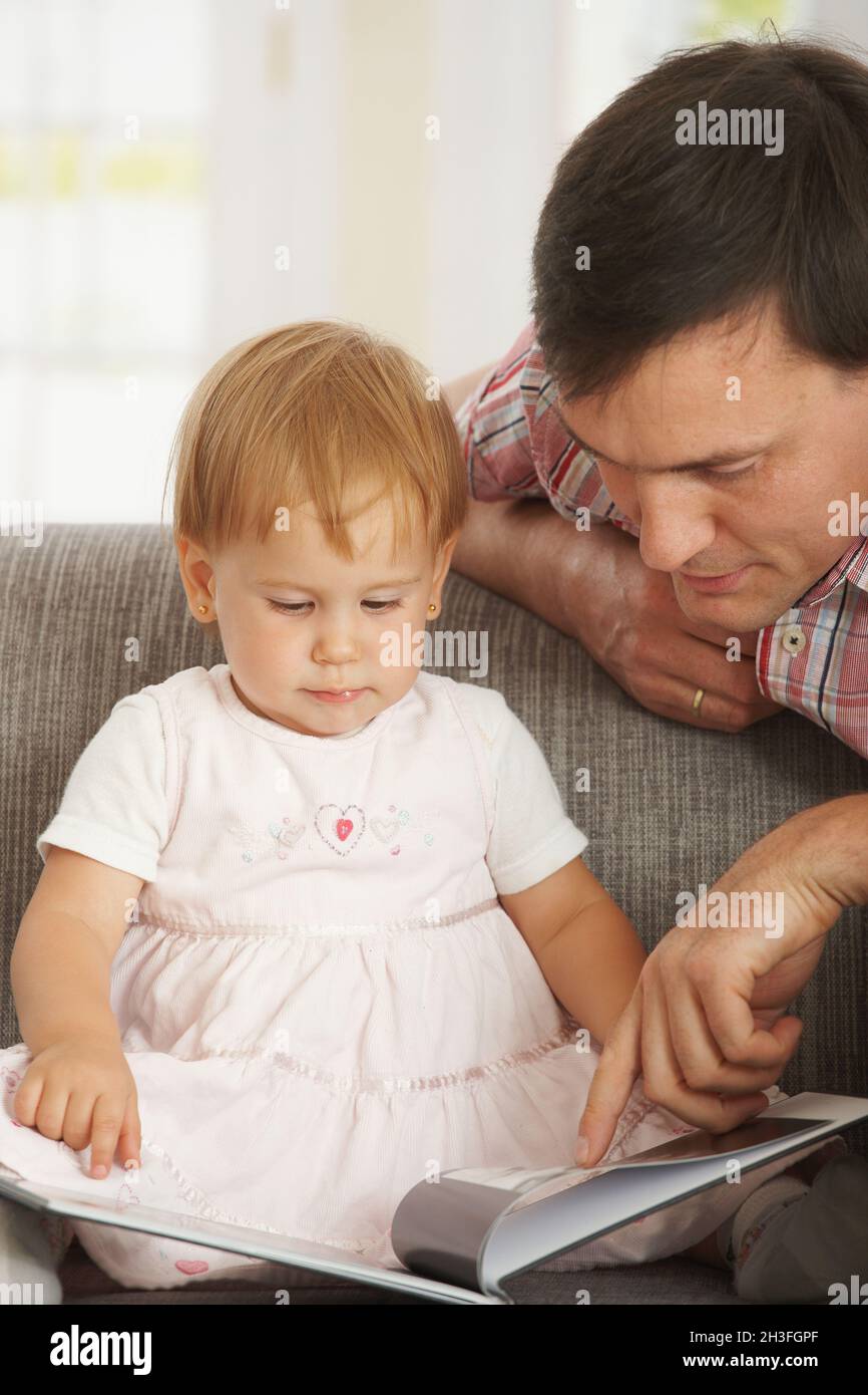 Father and baby reading book on sofa Stock Photo - Alamy
