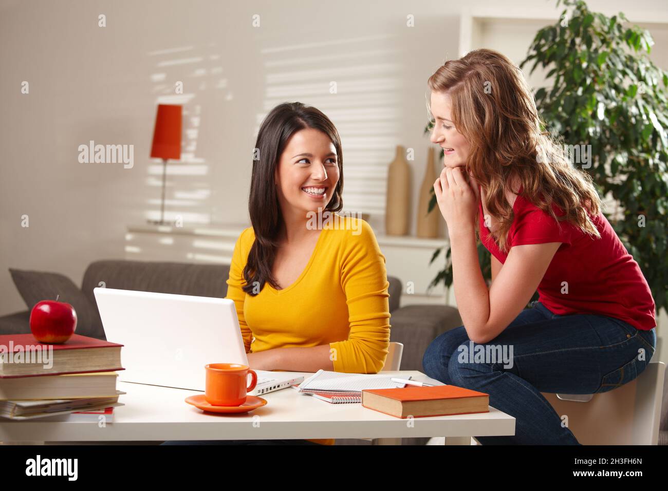 Two girls laughing together at table Stock Photo - Alamy