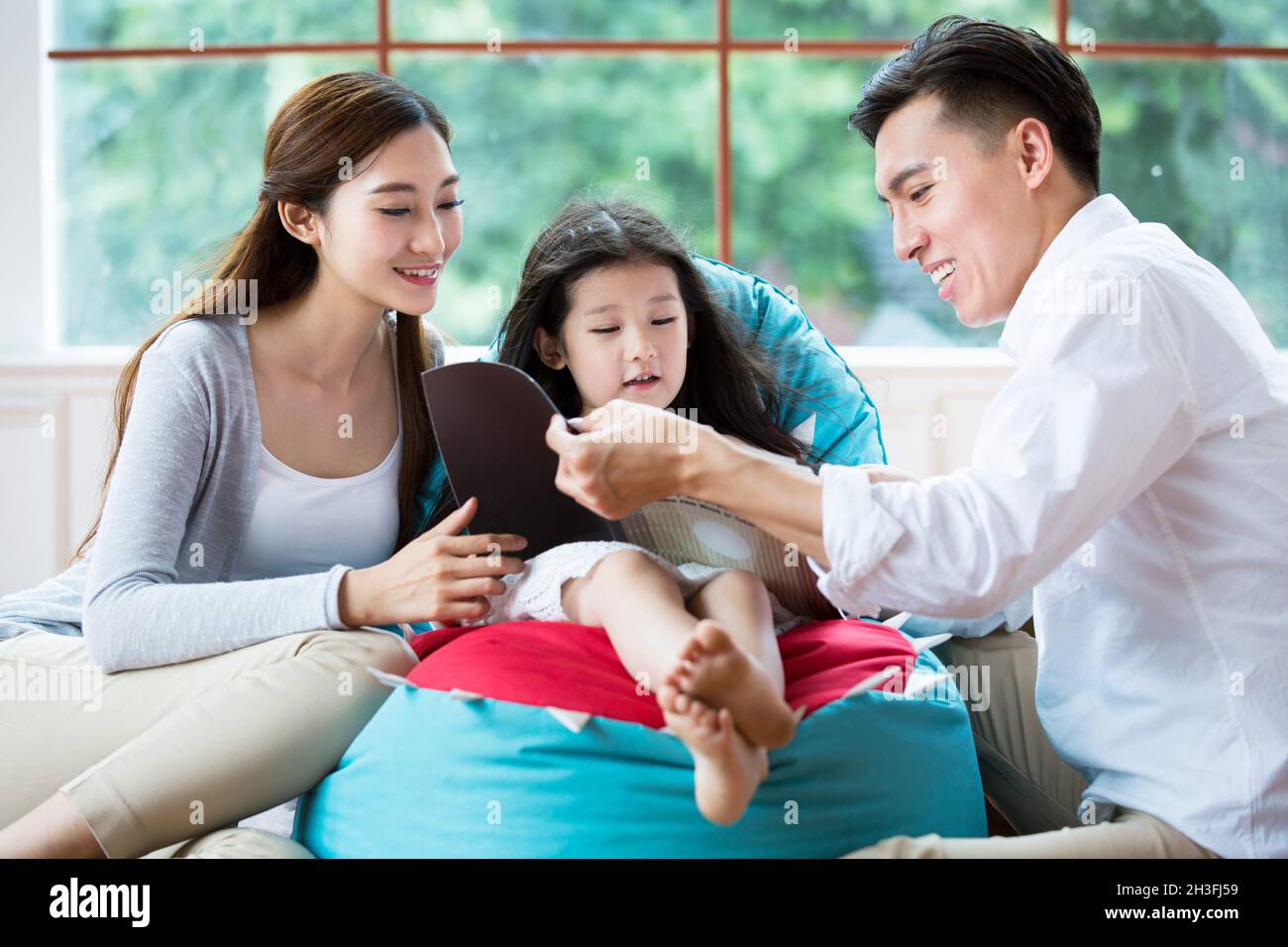 Young parents reading a book with their daughter Stock Photo - Alamy