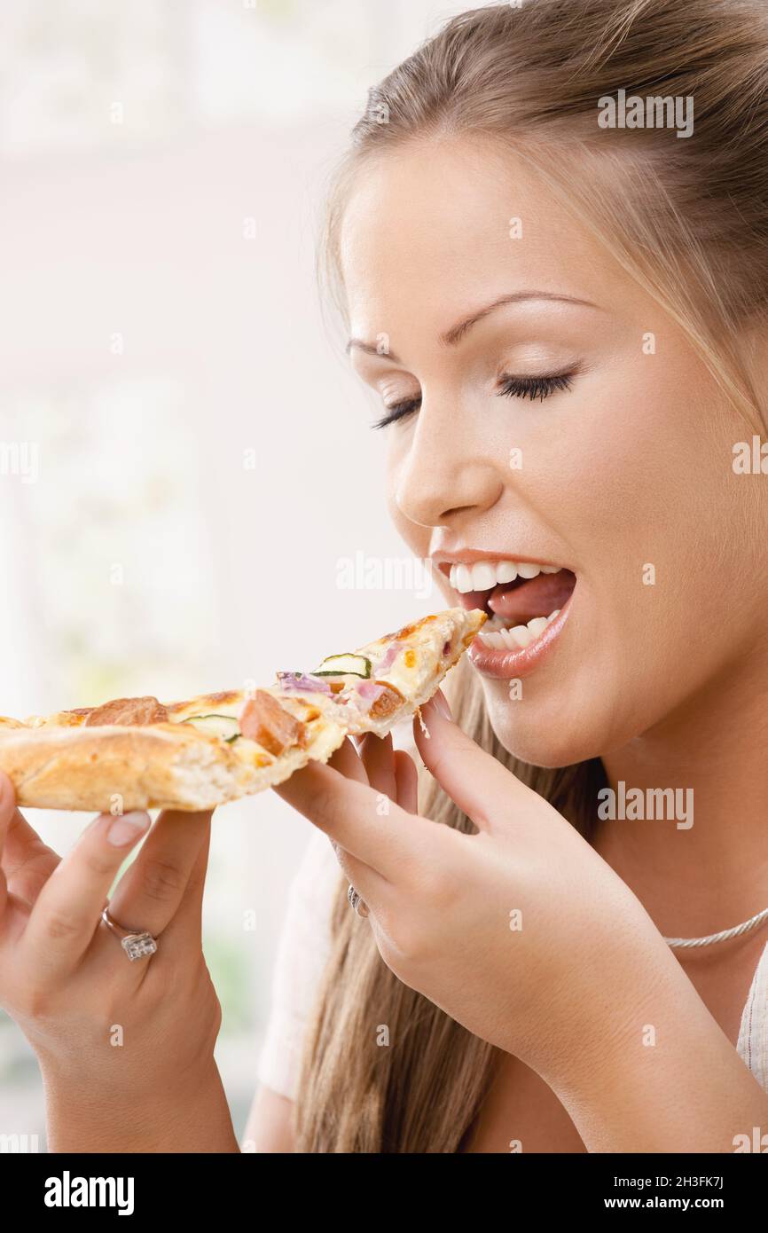 Young woman eating pizza slice Stock Photo - Alamy
