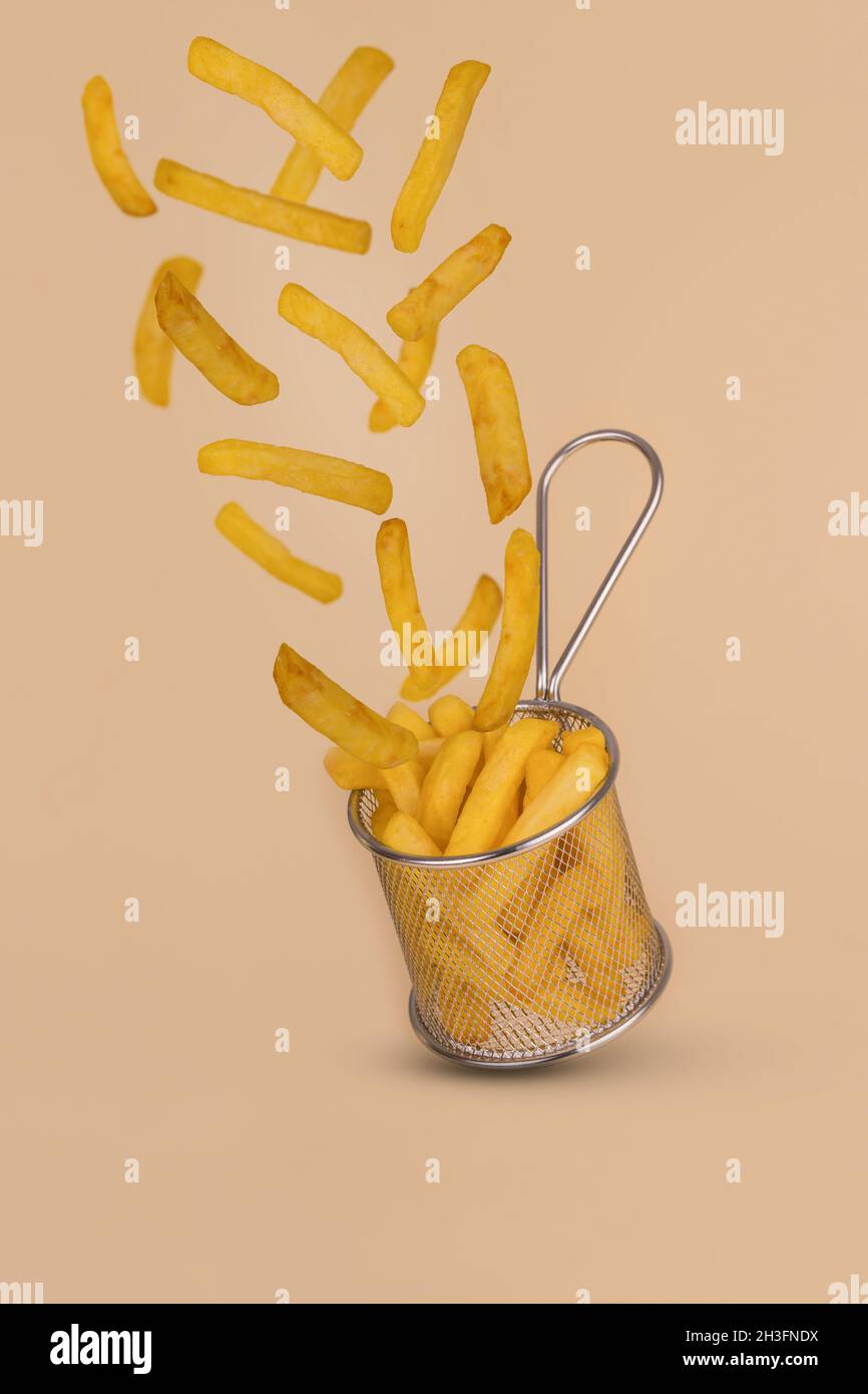French fries - fried potatoes flying out of basket. Fast food ...