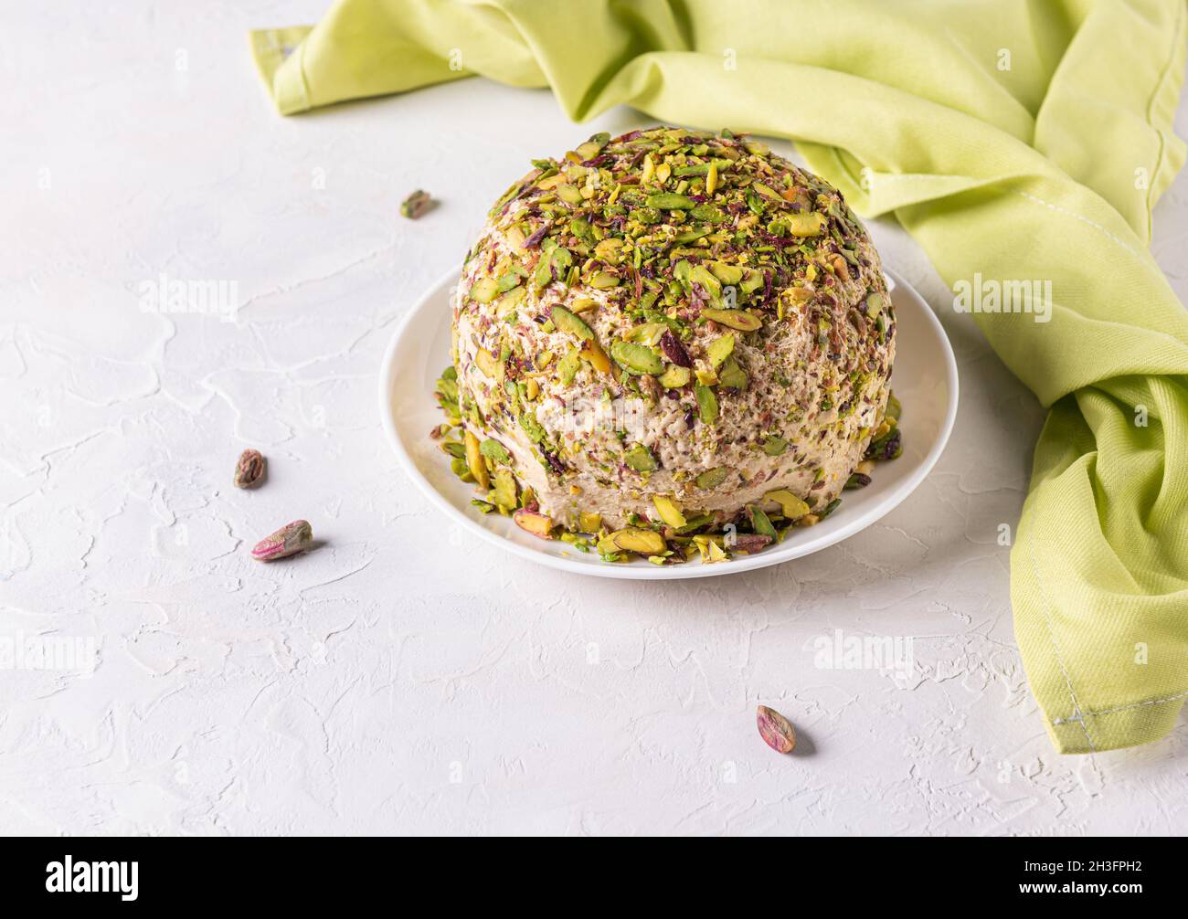 Ready to eat halva with pistachios on top, few scattered nuts, green ...