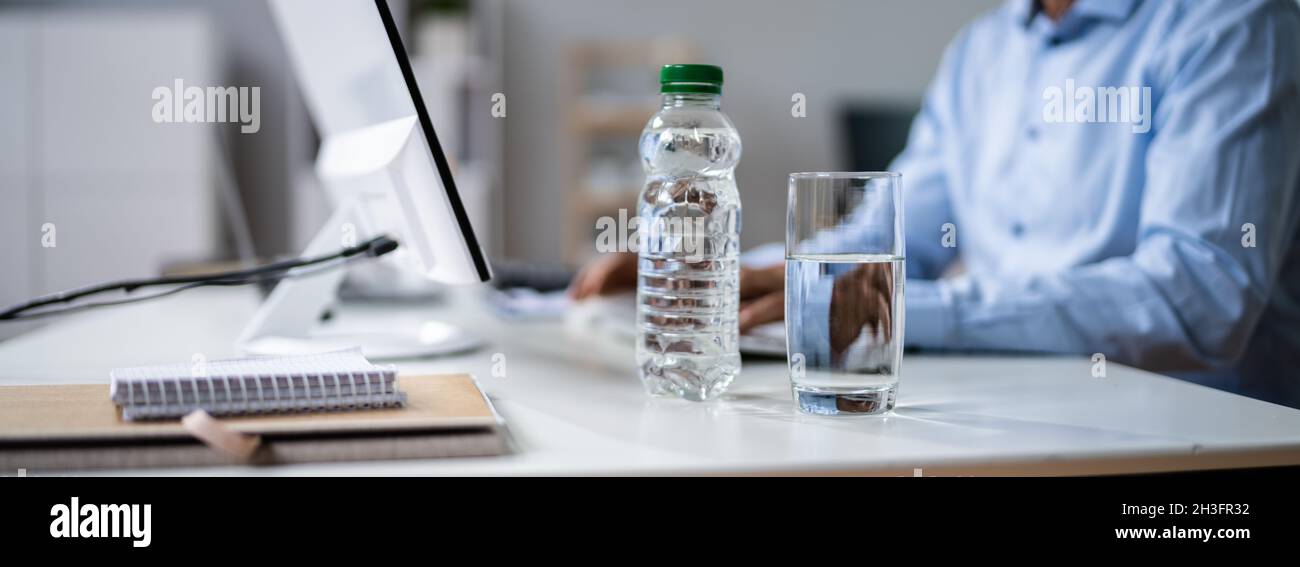 Water Bottle And Drinking Glass On Desk And Man Using Computer Stock ...