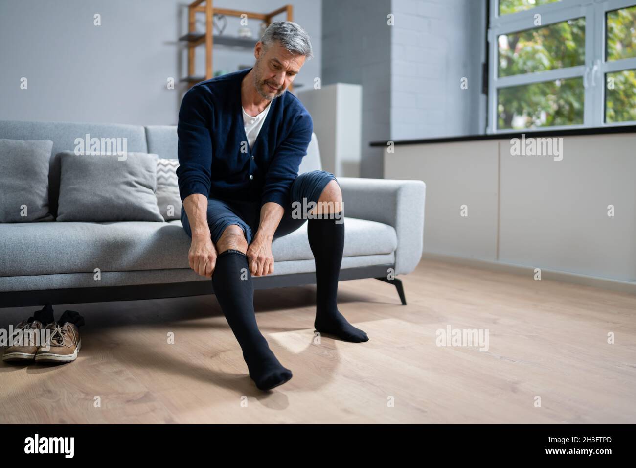 Man Putting On Medical Compression Stockings On Legs Stock Photo - Alamy