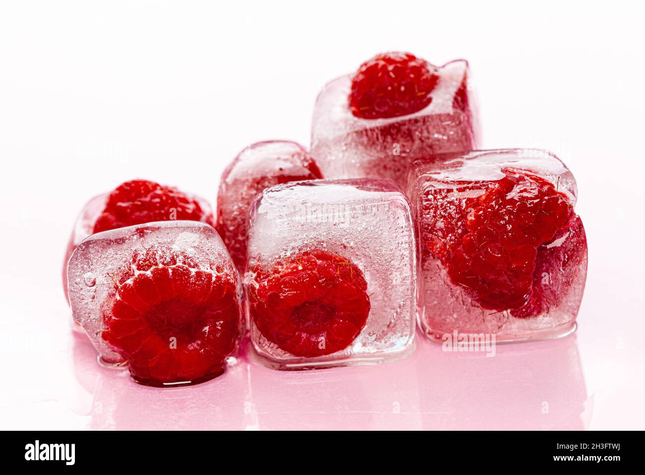 Raspberry ice cubes on pink glossy background Stock Photo - Alamy
