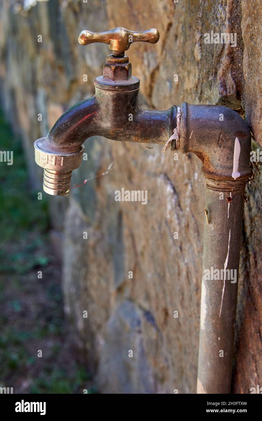 closeup profile of a closed bronze faucet on a wall outdoors. selective ...