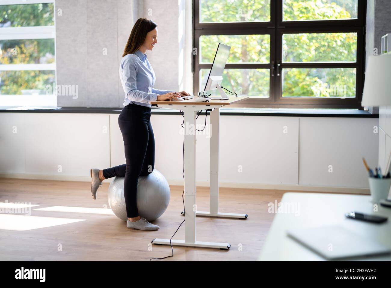 Woman Using Adjustable Height Standing Desk In Office For Good Posture ...