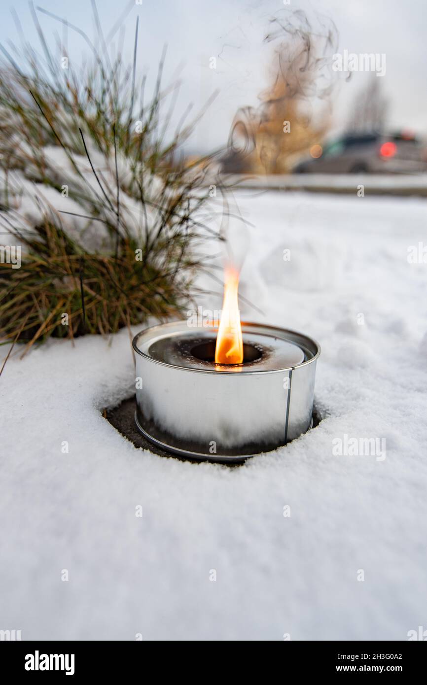 Vertical shot of a can with a fire flame in the snow Stock Photo - Alamy