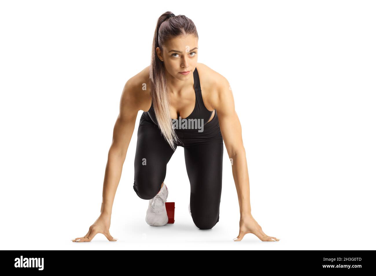Young female runner in a crouch start position isolated on white ...