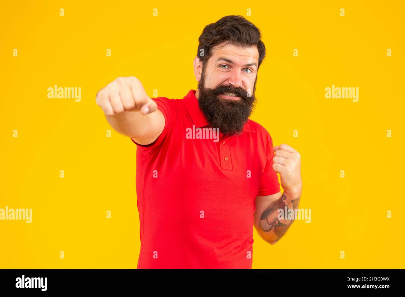 aggressive guy with beard and hairstyle punching on yellow background ...